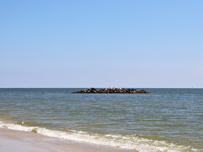 The rocky jetty creates calm waters on one side, proving that sometimes barriers make things better, not worse.