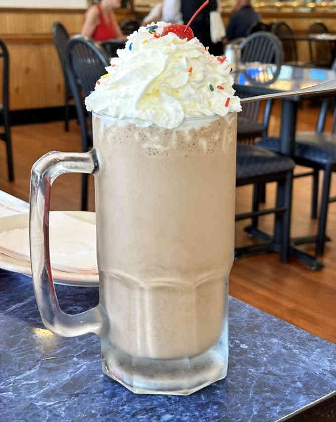 A milkshake topped with enough whipped cream to require its own zip code and possibly a ladder.