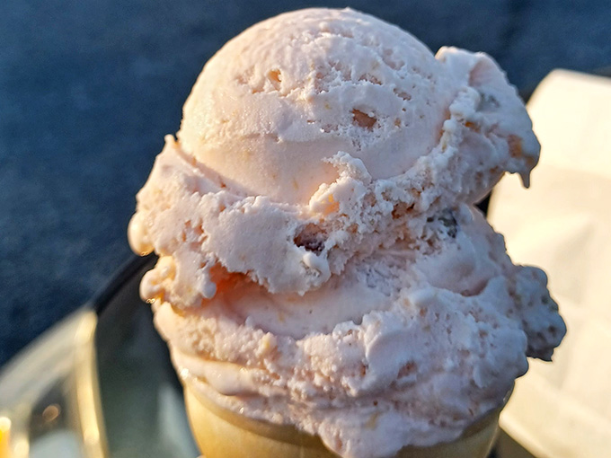 Creamy peach pecan ice cream stacked high like a delicious Leaning Tower of Pisa in your hand.