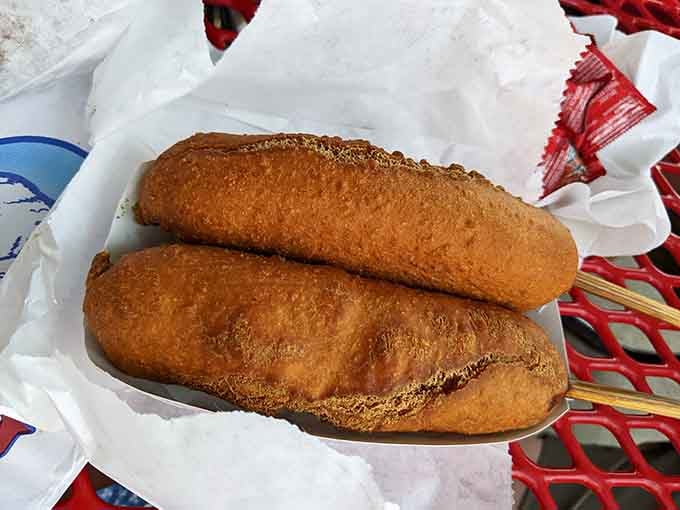 Two perfectly fried corn dogs that look like they just graduated from the state fair with honors in deliciousness.