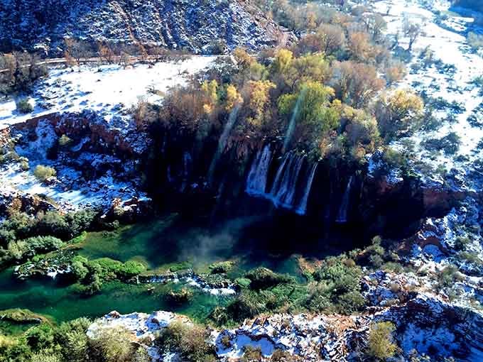 From above, the falls reveal their full glory, surrounded by snow-dusted canyon walls and emerald pools below.