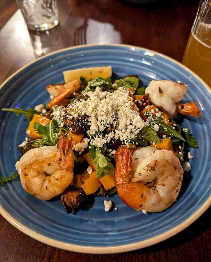 Jerk shrimp dancing atop fresh greens with roasted vegetables, proving fusion done right transcends all borders beautifully.