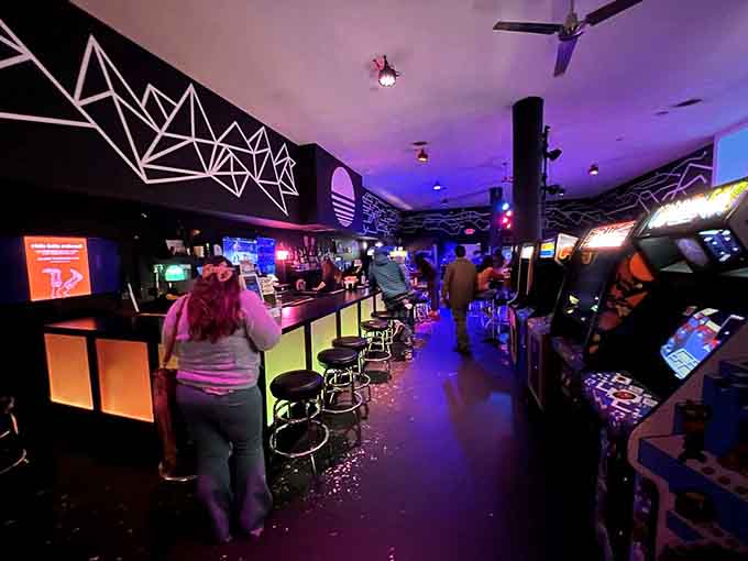 The bar stretches invitingly alongside arcade cabinets, creating the perfect balance between refreshment and entertainment.