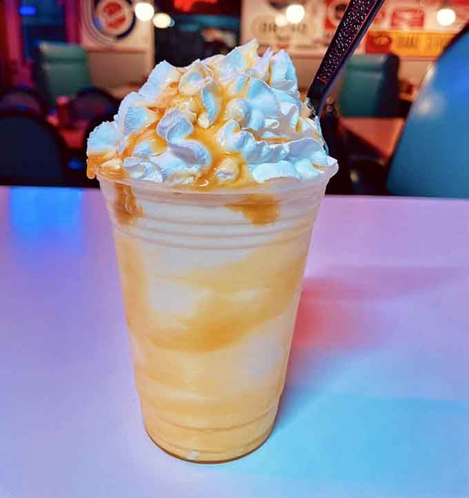 This towering milkshake with its caramel drizzle and whipped cream crown is pure nostalgic indulgence in a glass.
