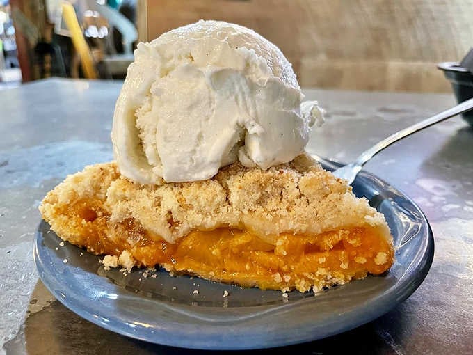 Peach cobbler pie topped with vanilla ice cream, proving that some combinations are simply meant to be together forever.