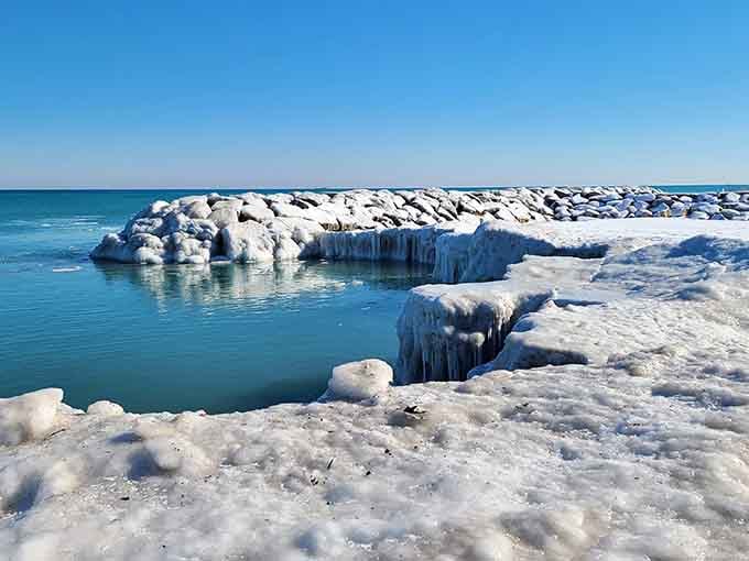 Winter transforms the breakwater into an ice sculpture gallery, proving this beach delivers drama in every season.