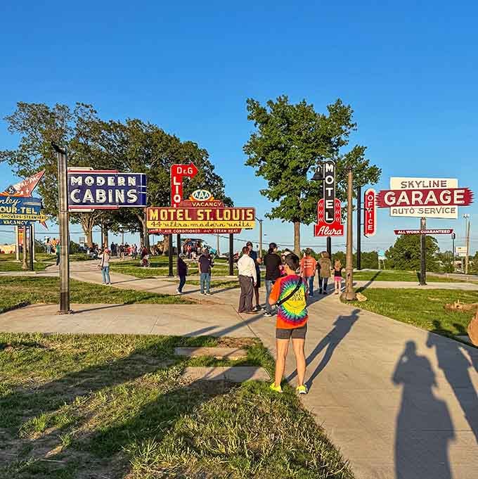 Visitors stroll among the towering signs, dwarfed by these magnificent monuments to mid-century American roadside culture and commerce.