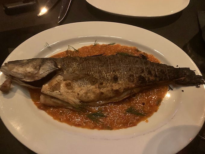 Whole roasted branzino arrives like it's ready for its close-up, swimming in a pool of aromatic sauce.