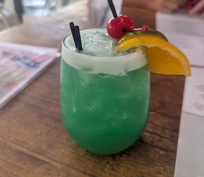 That emerald cocktail garnished with orange and cherry brings tropical vacation vibes to the desert landscape perfectly.
