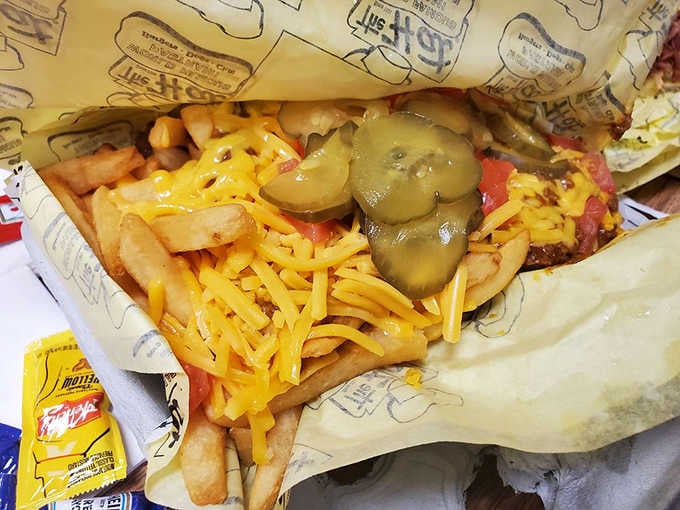 Chili cheese fries buried under toppings like treasure, requiring strategic excavation and multiple napkins for success.