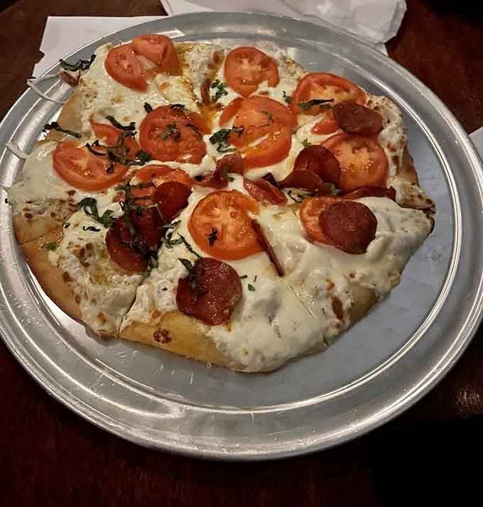 Fresh tomatoes and melted cheese on a silver platter, because even underground bars understand pizza's universal appeal perfectly.
