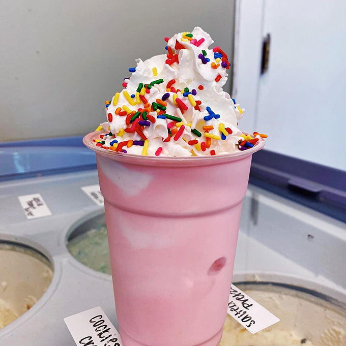 A pink milkshake topped with whipped cream and sprinkles, because adulting means ordering dessert whenever you want.