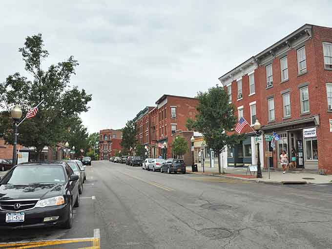 American flags flutter above brick buildings where patriotic spirit and small-town values remain alive and genuinely celebrated every single day.