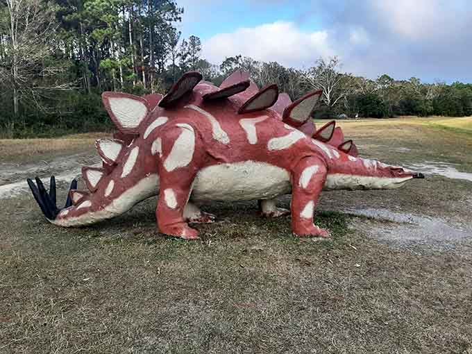 Red and white plates create dinosaur skin texture on this stegosaurus, its spiky back rising dramatically from the dusty ground.