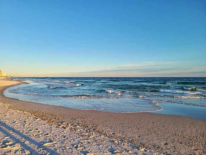 Sugar-white sand meets turquoise water under a golden sky that looks painted by an overly optimistic artist.