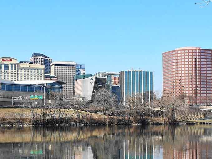 Modern towers reflect in the calm water while bare trees wait patiently for spring's arrival.