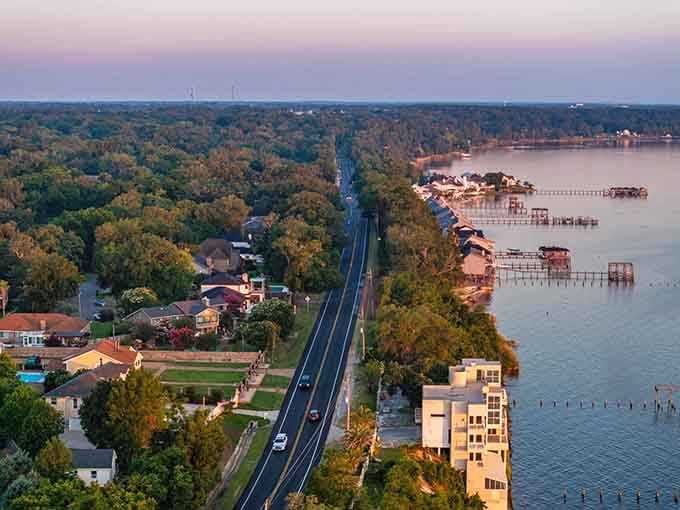 Sunset paints the waterfront in soft pastels while the road quietly connects neighborhoods to their liquid backyard.
