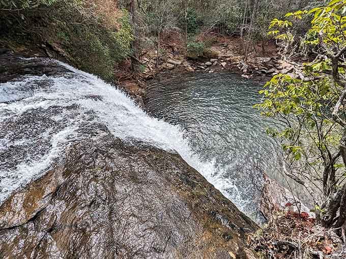 Swift water rushes over smooth granite into a dark pool surrounded by autumn's first colorful whispers.