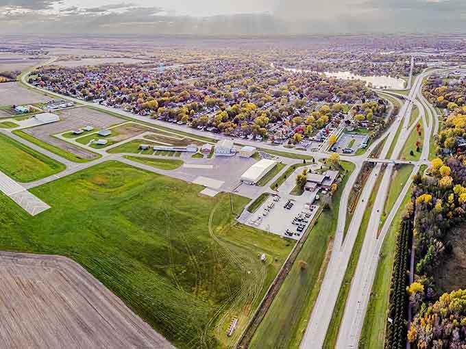 Bird's-eye perspective shows farmland meeting small-town America, where autumn trees paint the landscape in nostalgic golden hues.