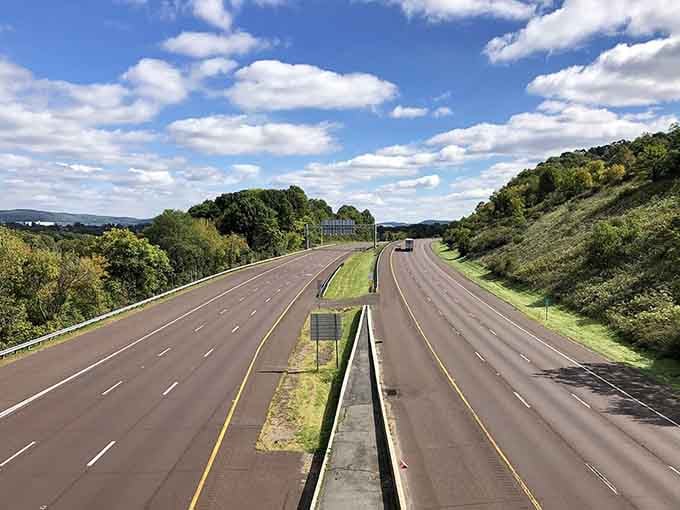 Rolling hills frame the open road like nature's own welcome mat, inviting you to explore what lies beyond the next curve.