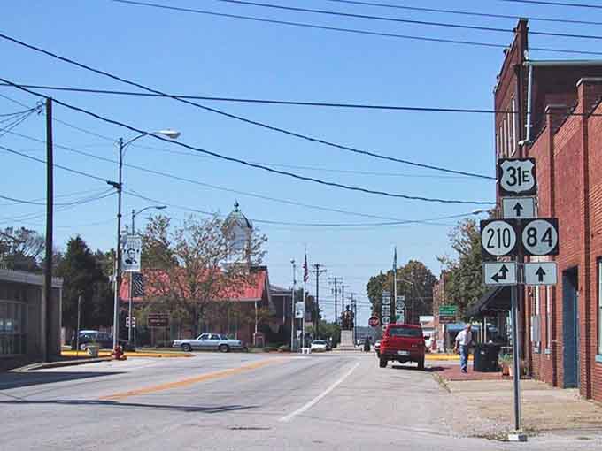 Highway signs point the way like breadcrumbs leading home, guiding travelers to discover this quiet corner of authentic America.