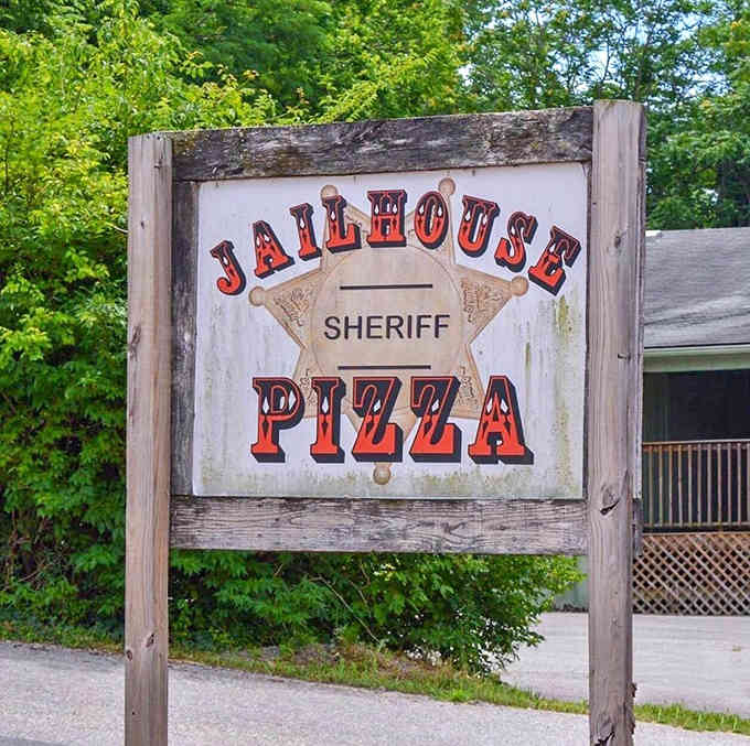 The weathered wooden sign with sheriff's badge proves even former jails can find redemption through delicious food.