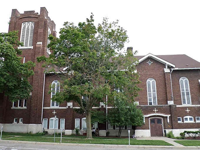 Brick and trees frame this historic church, where generations have gathered under that distinctive tower for comfort.