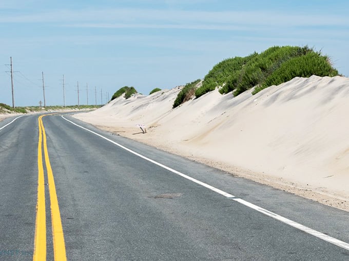 Sand dunes rise like frozen waves beside the coastal highway, where the landscape feels more Sahara than seashore.