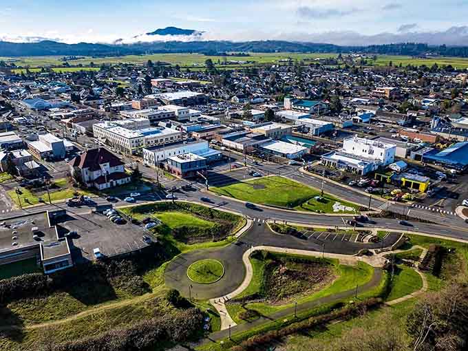 From above, the town spreads across green fields like a well-planned neighborhood, mountains rising majestically in the misty distance beyond.
