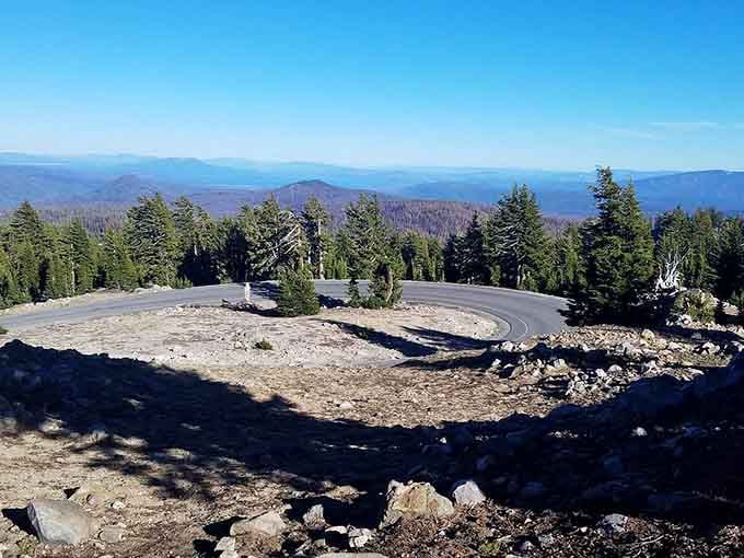 This hairpin turn at elevation offers views that stretch forever, where mountain ridges fade into misty blue horizons.