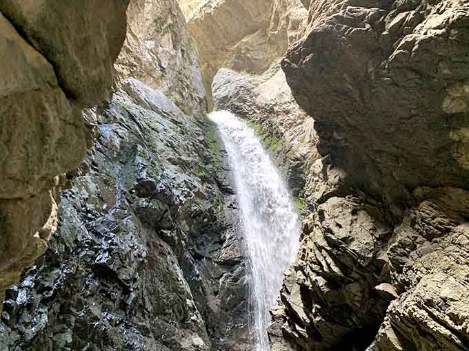 Sunlight filters through the narrow opening, illuminating the falls like a natural spotlight on opening night.