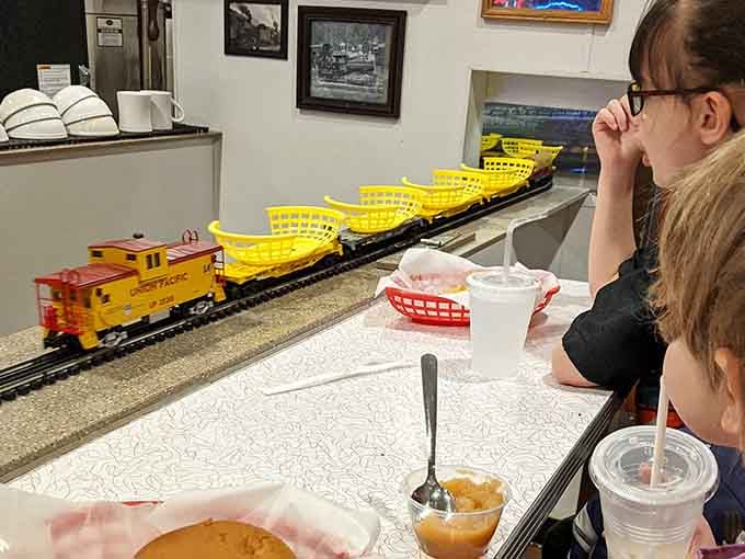 Yellow baskets loaded with lunch cruise the overhead tracks, turning dinner into dinner theater for all ages.