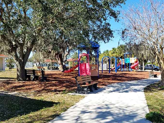 Colorful playground equipment dots this shaded park where oak trees provide natural air conditioning and kids still play outside.
