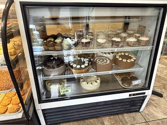 The cake cooler showcases everything from simple rounds to elaborate creations, all waiting for their special occasions.