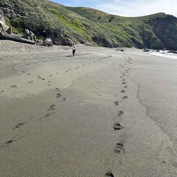Footprints trailing across dark sand tell stories of adventurers who earned this view the hard way.