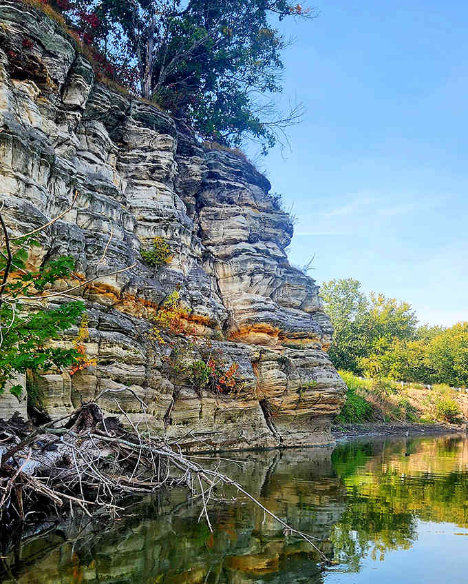 Ancient sandstone cliffs rising from calm waters, reflecting millions of years of geological history in one peaceful moment.