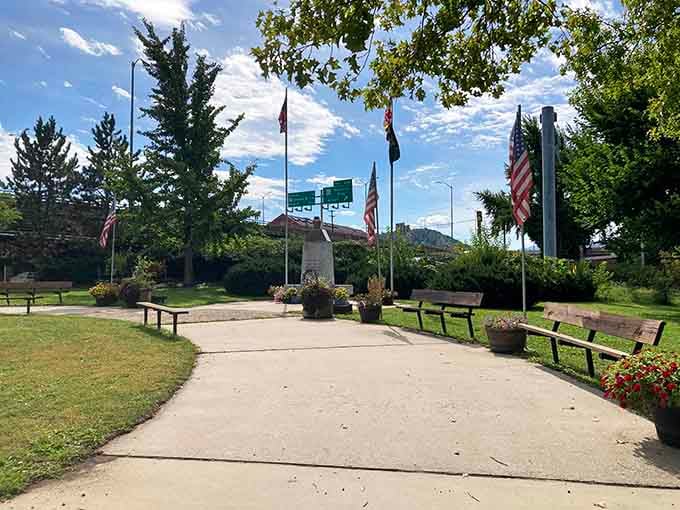 Flags flutter over this peaceful memorial park, where benches invite reflection and mountains provide the perfect backdrop.