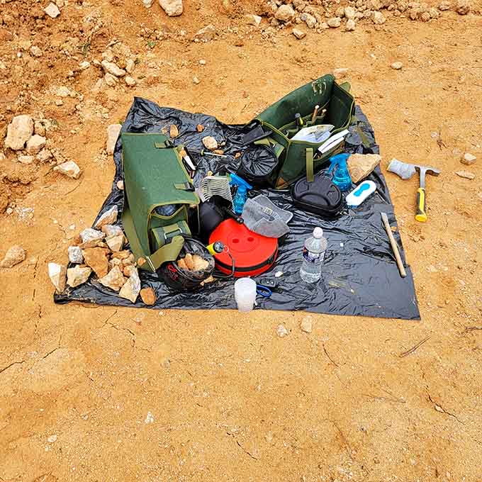 The serious rockhound's arsenal: tools, water, snacks, and optimism spread out like a geological picnic.