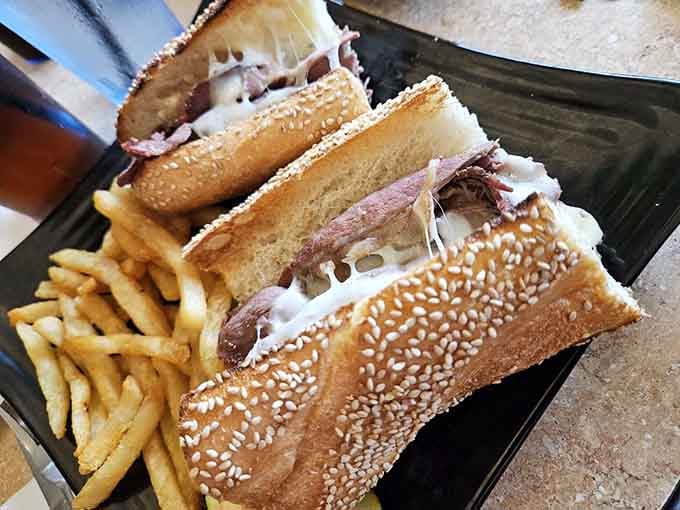 Roast beef and cheese on a sesame seed roll with fries—classic sandwich perfection that never goes out of style, no matter the decade.