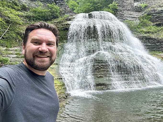 That genuine smile says it all: standing before this waterfall beats any virtual reality experience money can buy.