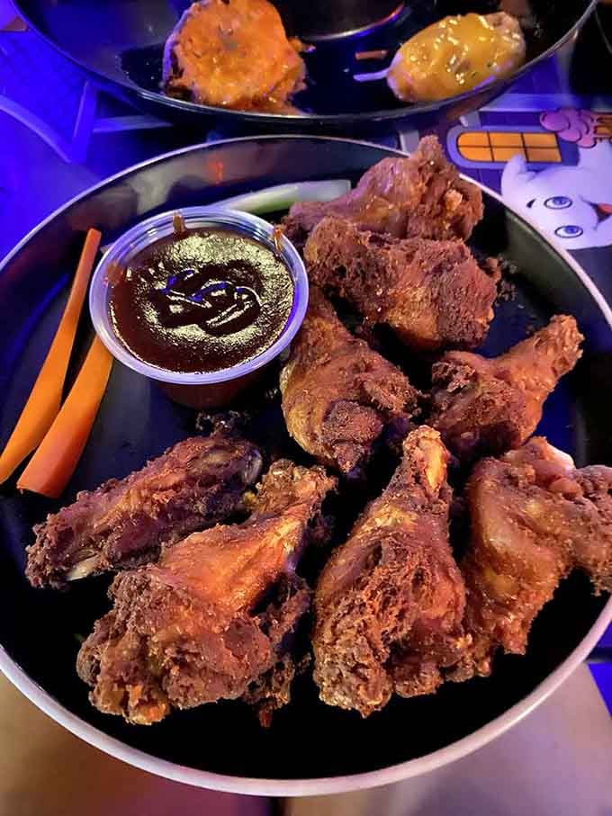 Crispy chicken wings arrive with sauce decorated in a spooky face, because even your appetizer deserves theatrical presentation here.
