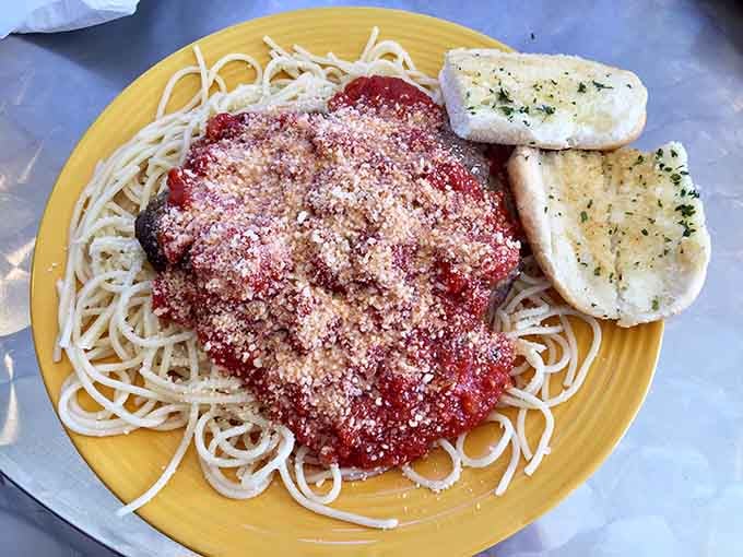 Spaghetti topped with marinara and parmesan on a sunny yellow plate delivers comfort food that hugs you back.