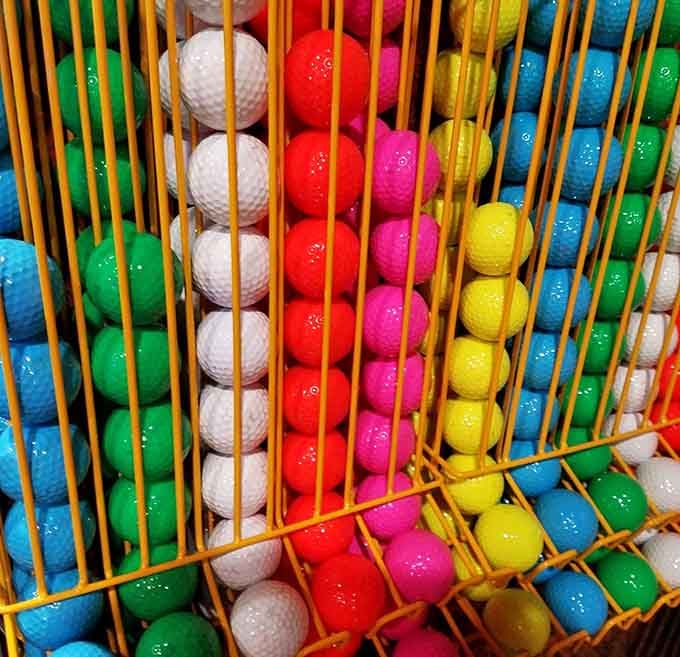 Rainbow golf balls wait patiently in their cage, each color representing another chance at that elusive hole-in-one glory.