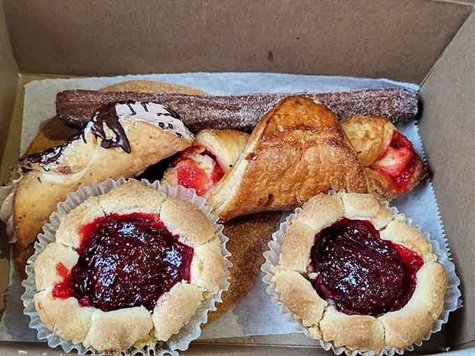 Jam-filled pastries, flaky turnovers, and a chocolate-drizzled churro sharing one box like old friends on a road trip.