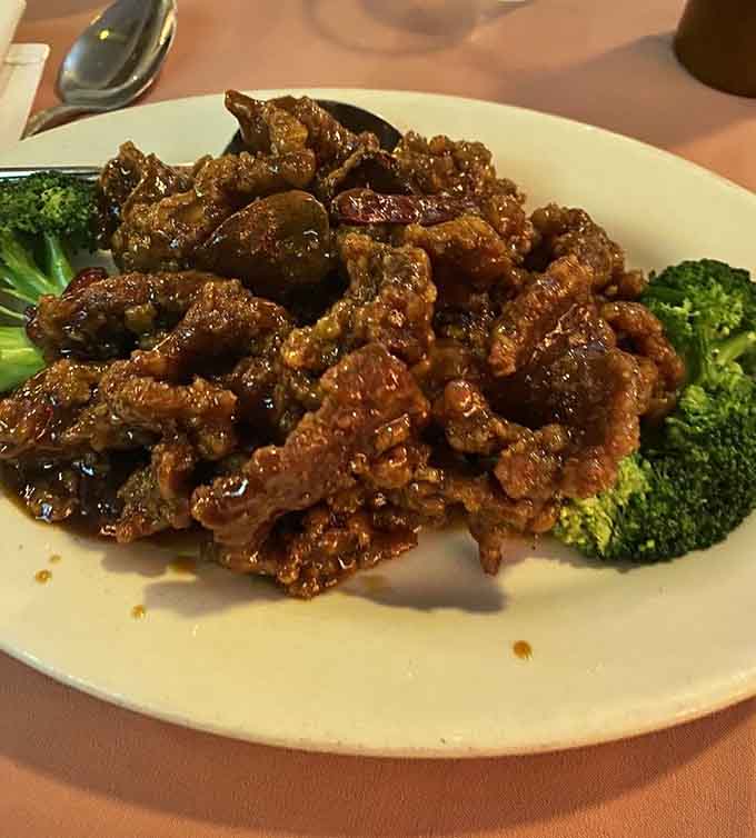 Orange beef glistens with that perfect sticky glaze, flanked by broccoli like tiny green palm trees on your plate.