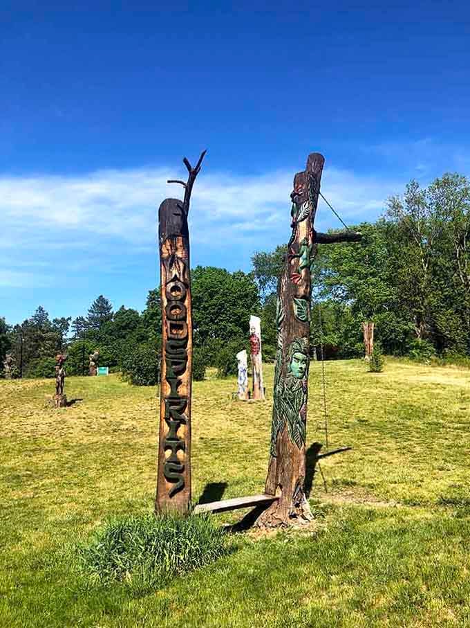 Multiple wooden totems standing together like they're having the world's most interesting sculpture convention on the arboretum lawn.