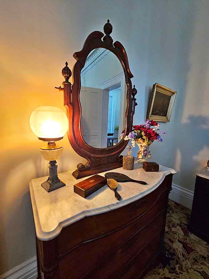 The warm glow from that antique oil lamp illuminates a marble-topped vanity where countless morning routines unfolded generations ago.
