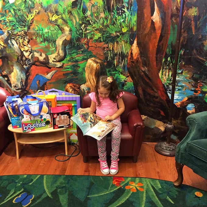 A cozy reading nook with that stunning nature mural where kids can actually sit and read, imagine that.