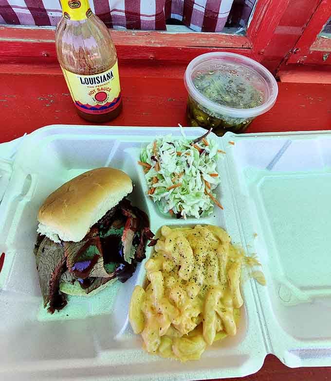 Beef brisket sandwich overflowing with smoky goodness, requiring both hands and possibly a construction permit.