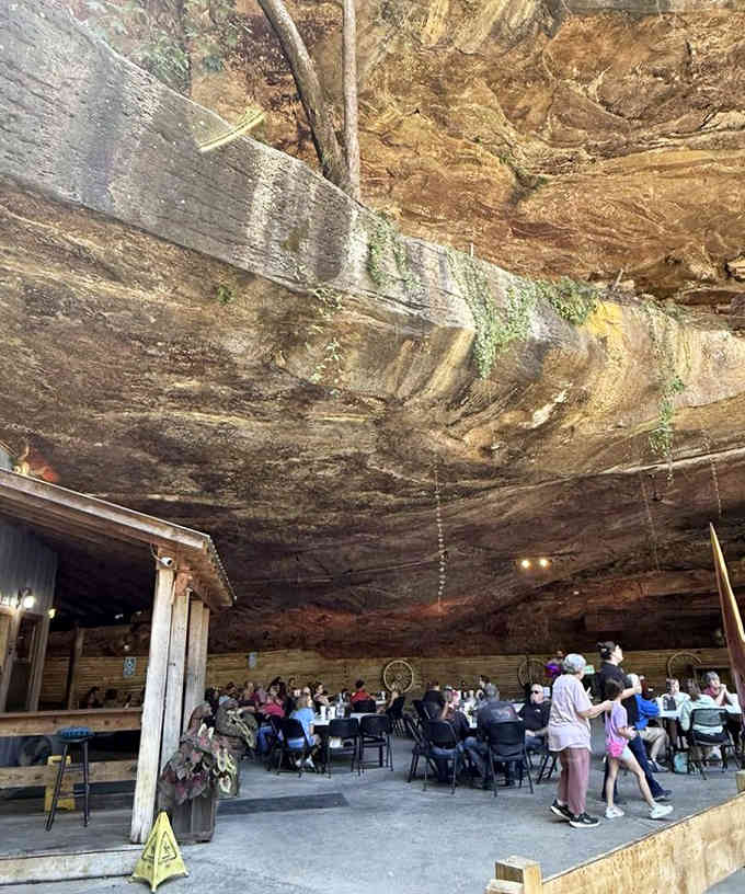 Families gather beneath ancient rock while moss clings to the ceiling above, creating the most unusual Sunday dinner backdrop imaginable.